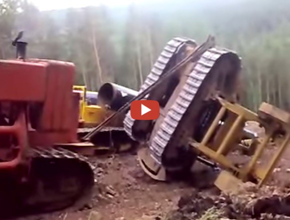 A bulldozer is stuck on its side so another one trys to help it but the ...