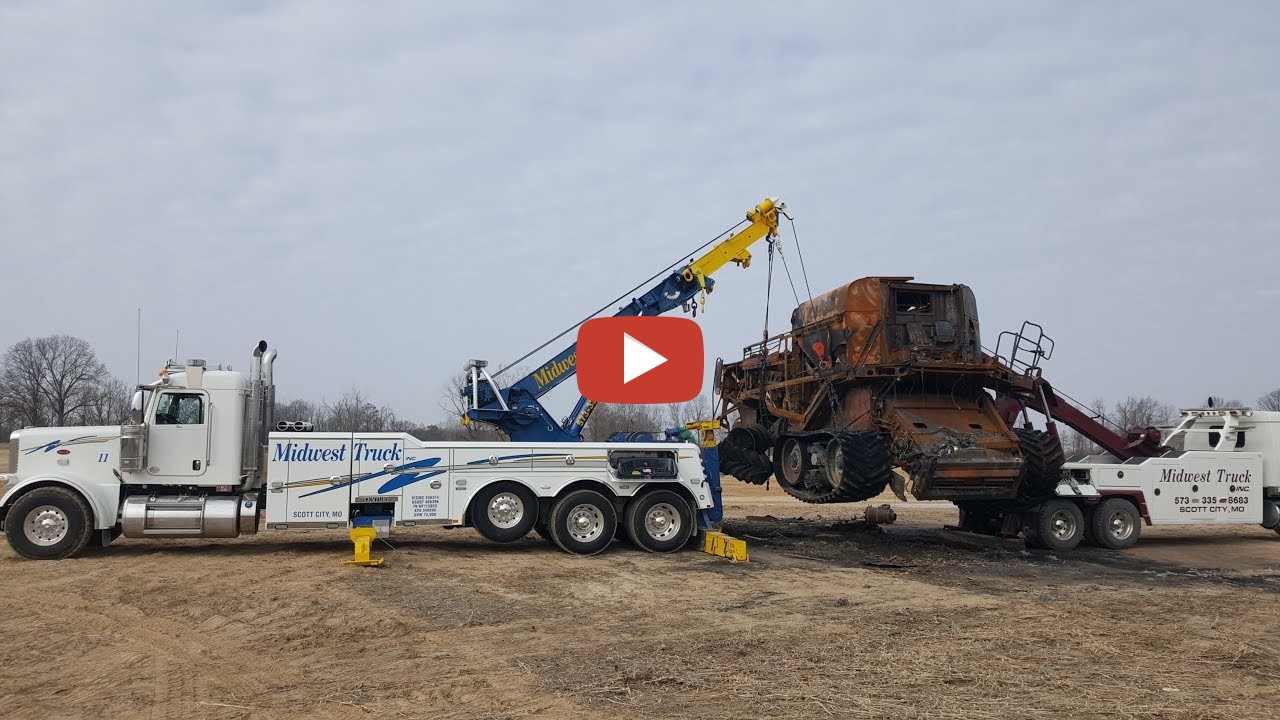 Lifting, loading, and cleaning up after a combine burnt in a field ...